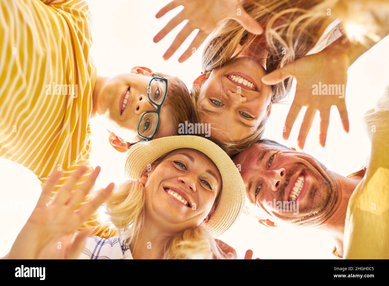 Parents and two children stand in a circle and wave happily as a happy ...