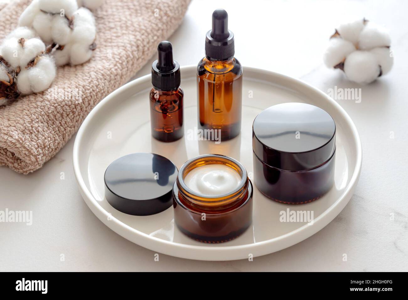 Set of amber glass cosmetic bottles on ceramic tray. dropper bottle and ...