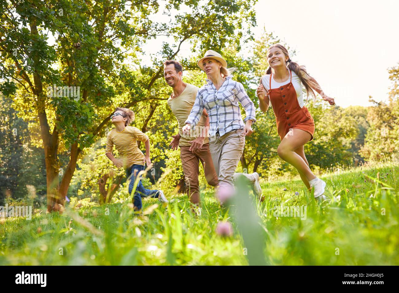 Happy family with two children have fun in a race in summer in nature ...