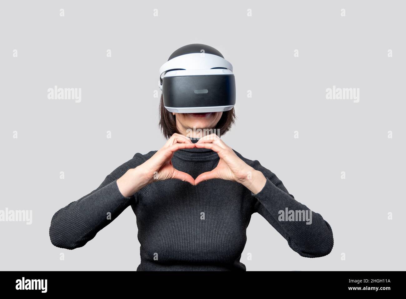 Beautiful woman using vr headset shows heart shape with hands isolated ...