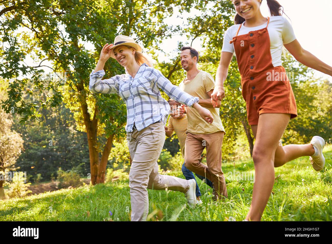 Happy family with two children running race in park on nature in summer ...