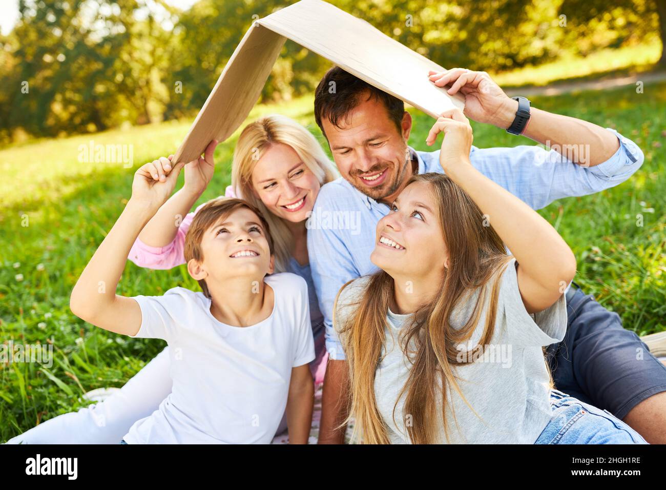 Parents and children hold roof over their heads in the park as a symbol ...