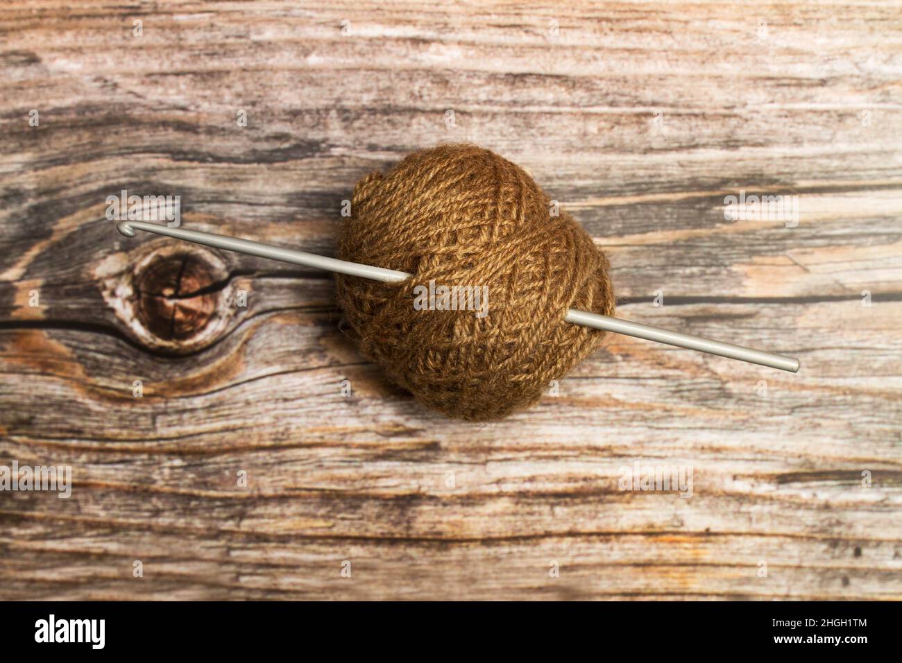 Brown wool spool and a crochet needle on a wooden background Stock ...