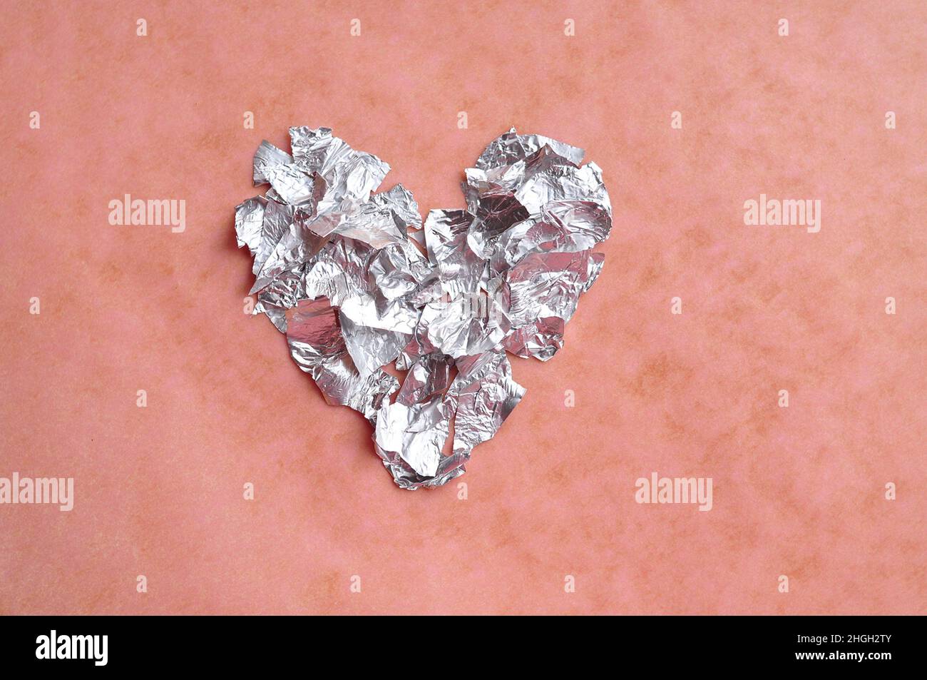 Steel foil heart on brown background postcard Stock Photo - Alamy