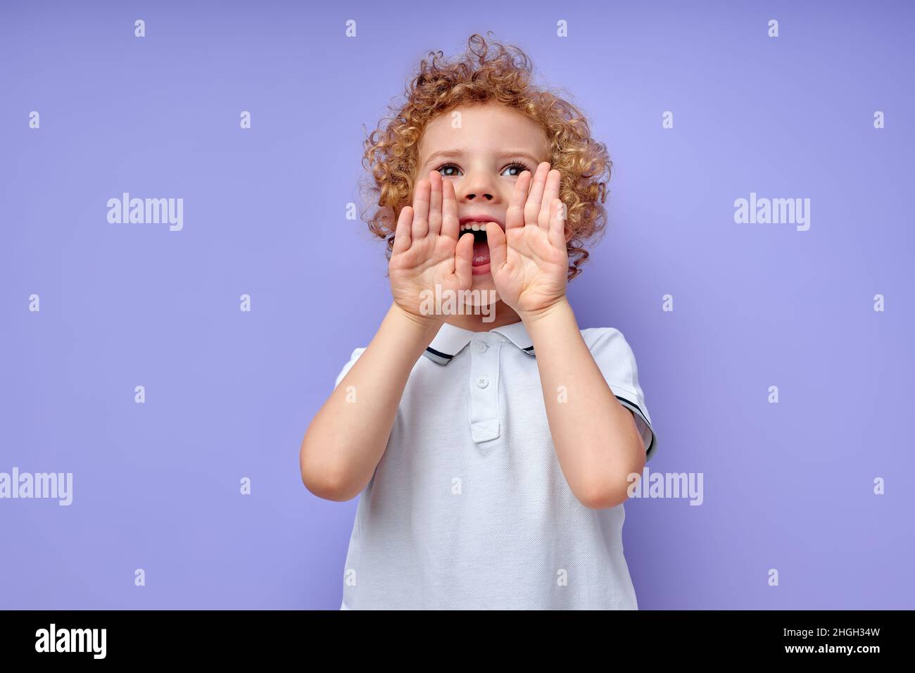 Little child yelling in amazement against purple studio background ...