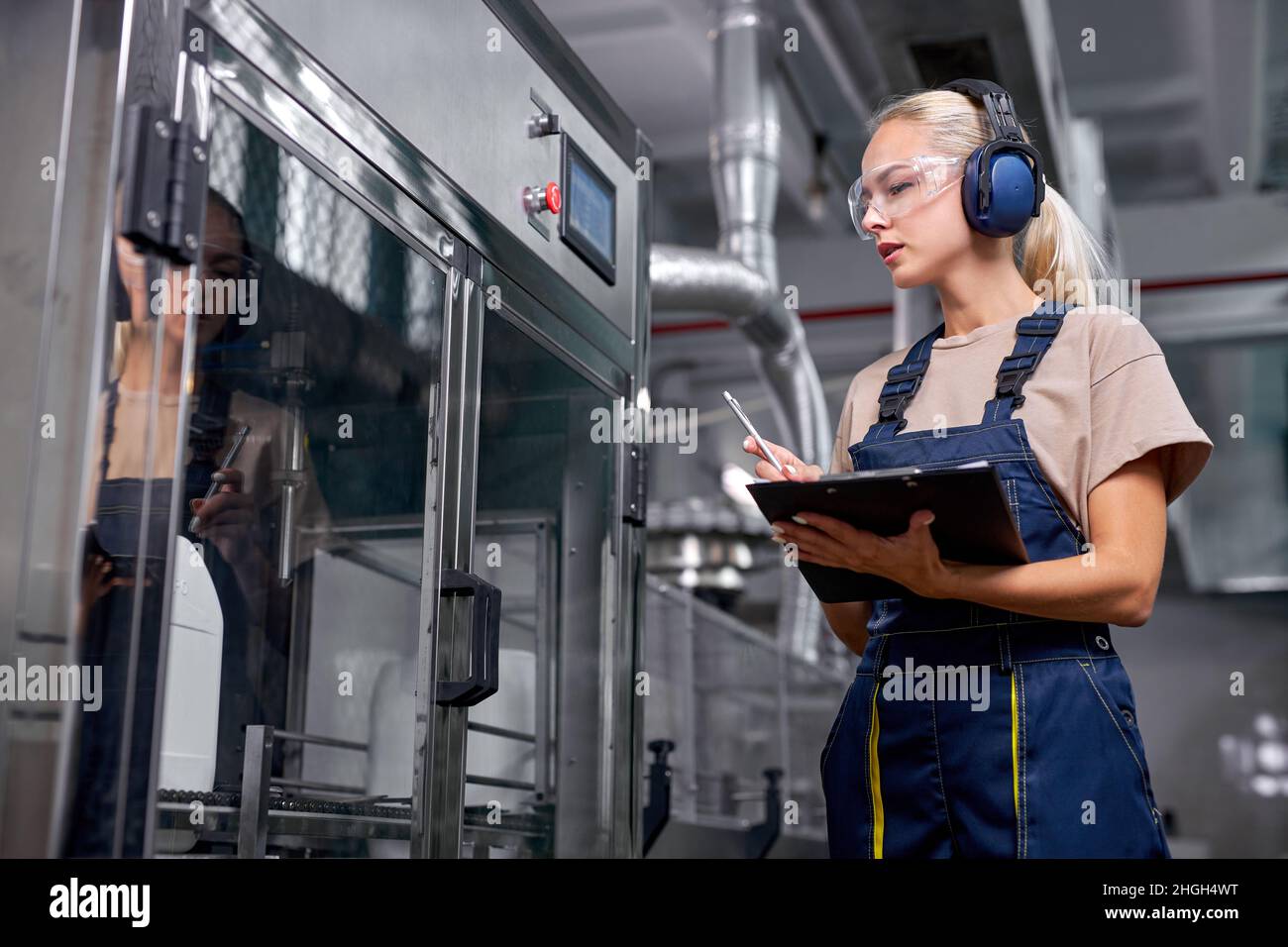 female factory worker hold quality control at work, take notes into ...