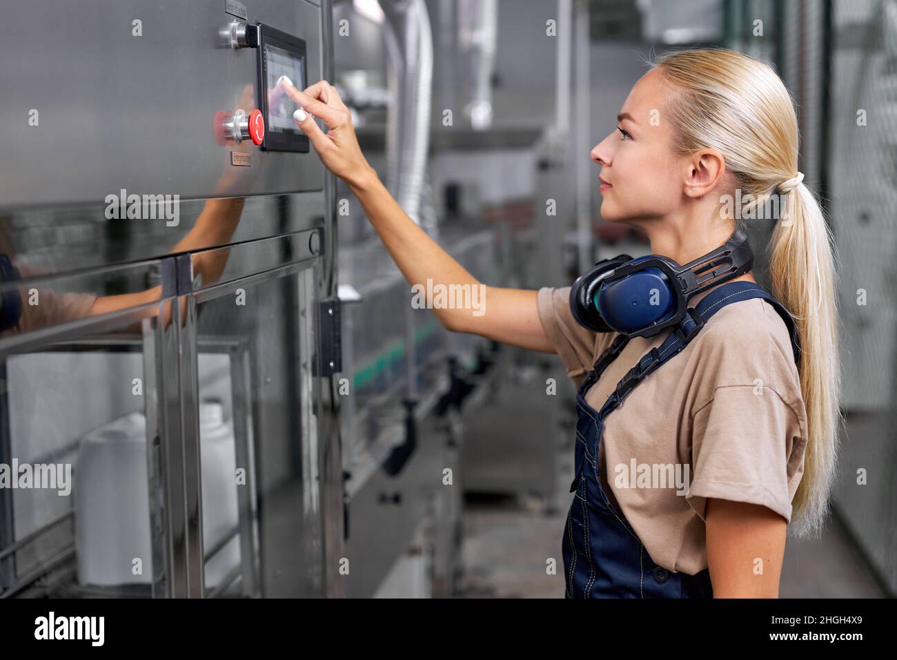 worker in factory checking robotic equipment for bottling and packing ...