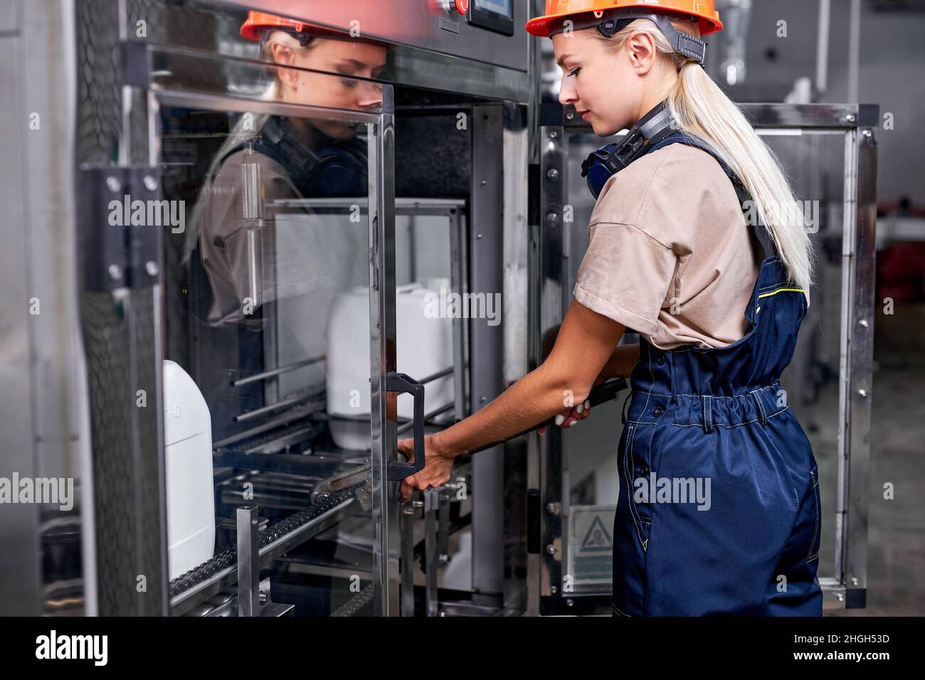 worker in factory preparing robotic line for bottling and packing ...