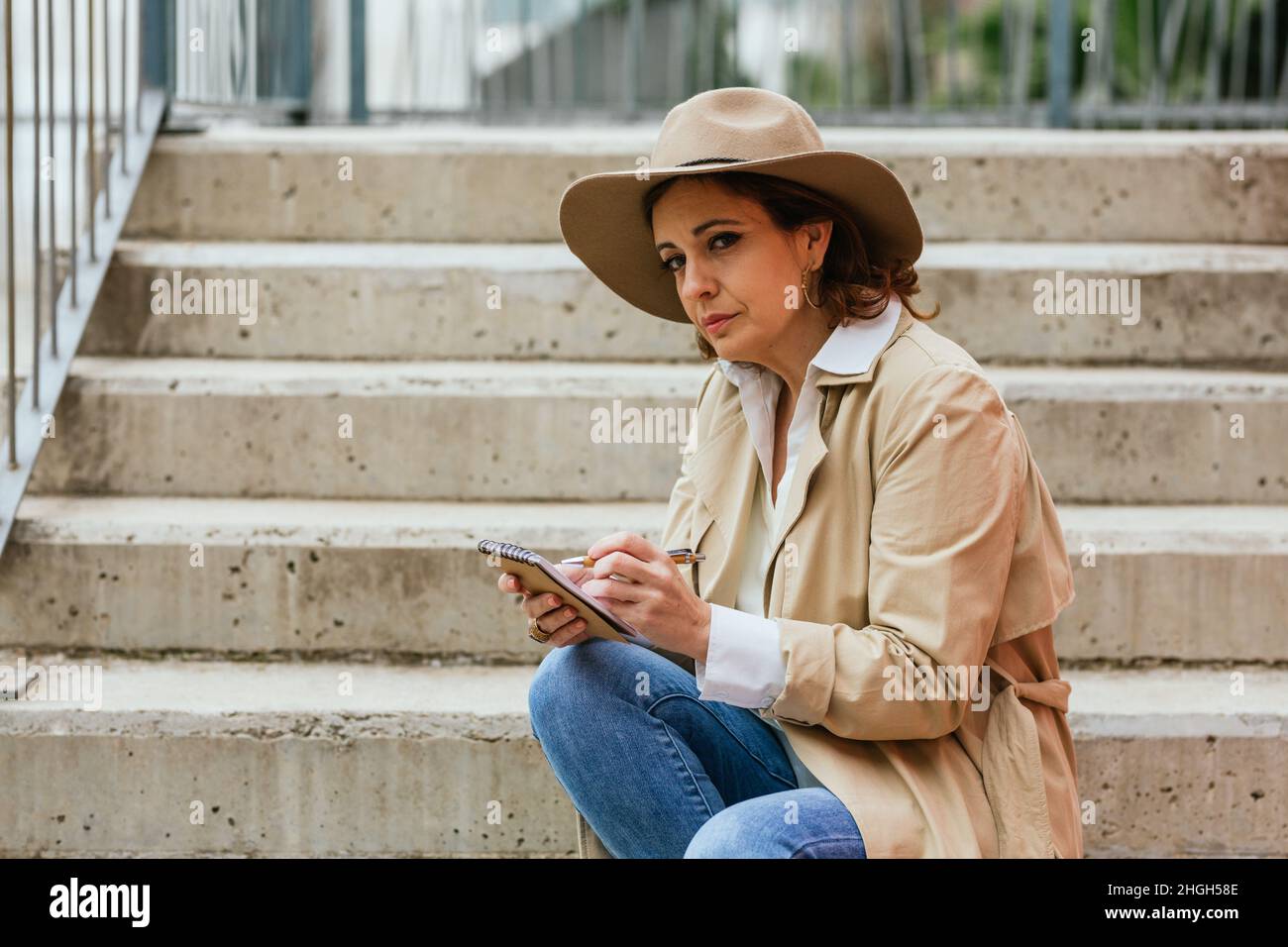 Woman taking notes and writing ideas in a notepad while sitting on the ...