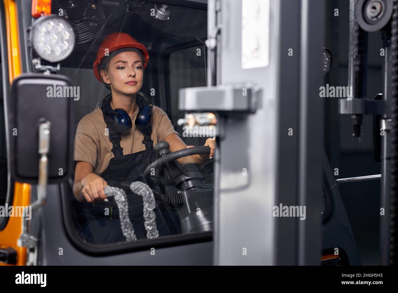 Beautiful woman forklift worker operator driving vehicle at warehouse ...