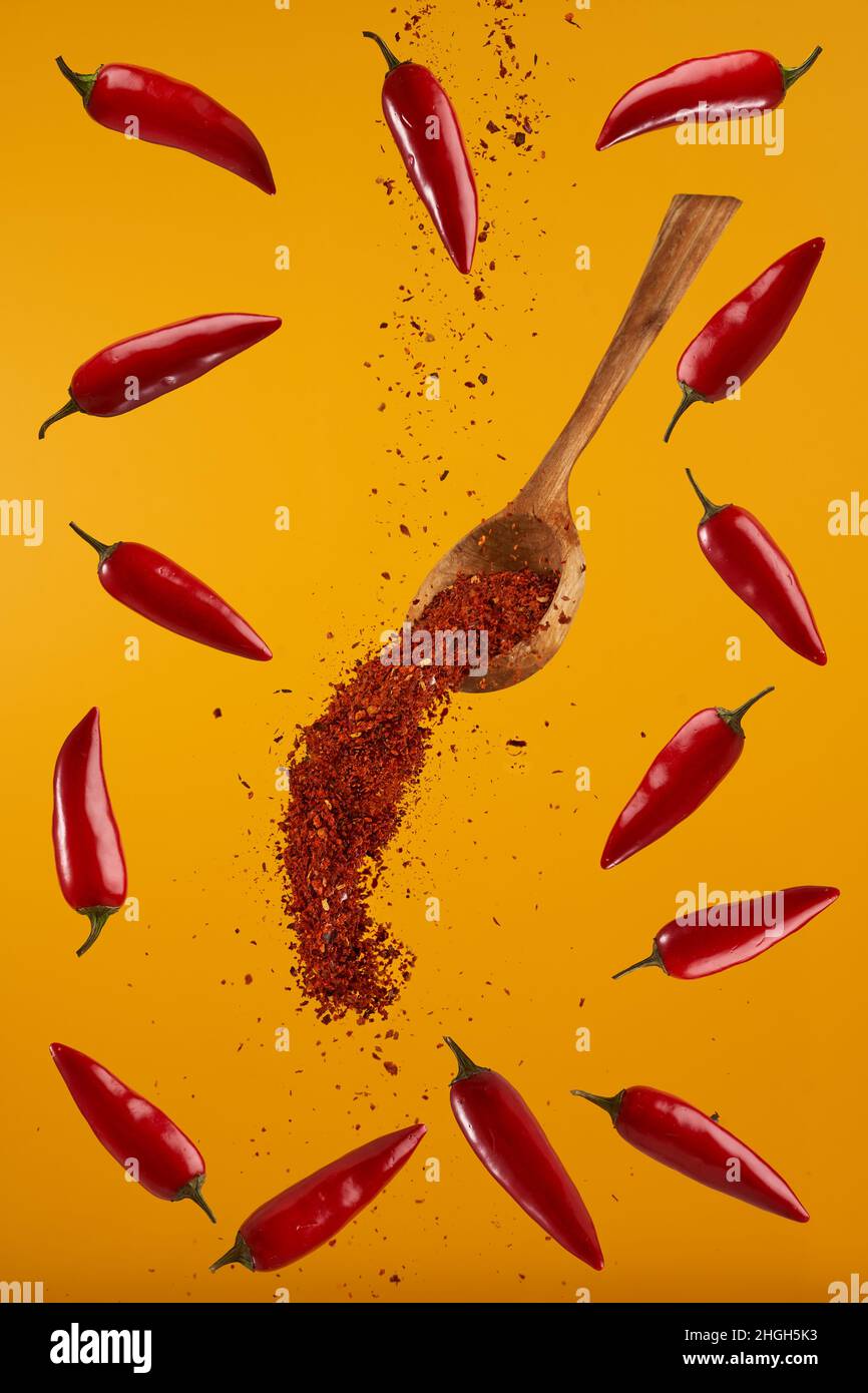 Flying hot chili and pepper flakes on yellow background Stock Photo - Alamy