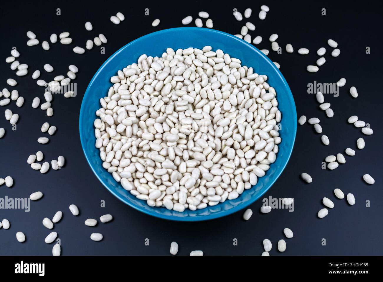 Small white beans on the green plate and black background. Raw white ...