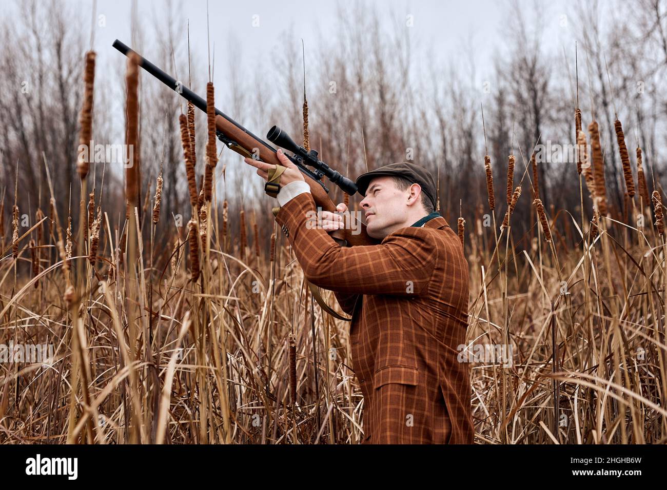 confident hunter wearing brown trendy suit and hat waiting for the bird ...