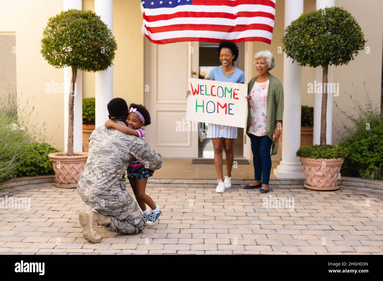 Smiling african american women looking at girl embracing father soldier ...