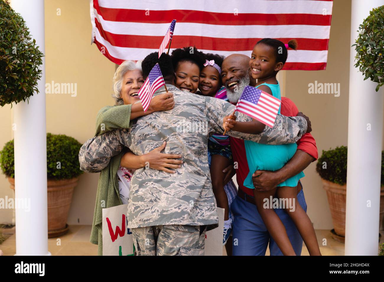 Happy african american family with usa flag hugging army soldier on his ...