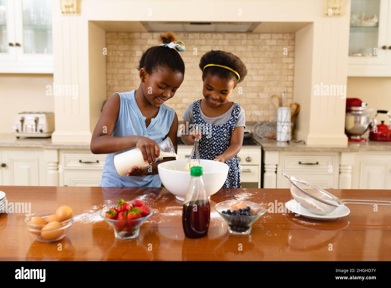 Two african american sisters baking together in the kitchen at home ...
