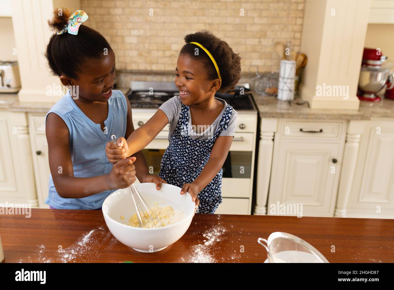 Happy two african american sisters baking together in the kitchen at ...