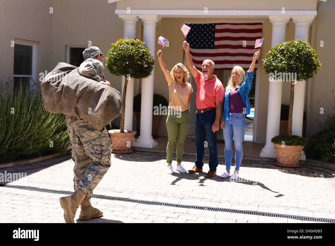 Excited caucasian family with flags cheering military soldiers return ...