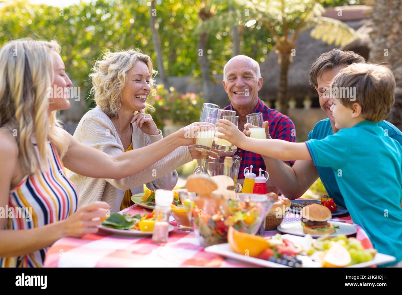 Happy caucasian three generational family toasting drinks at table in ...
