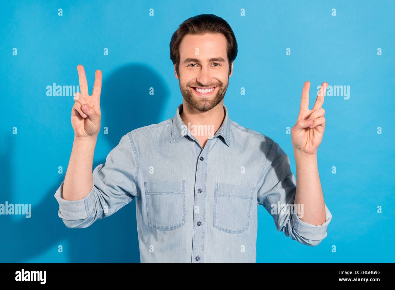 Portrait of attractive cheerful man employer showing double v-sign ...
