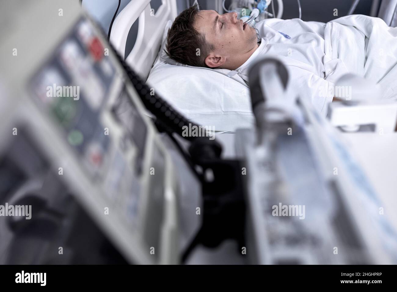 young injured man lying in bed hospital room resting from pain looking ...