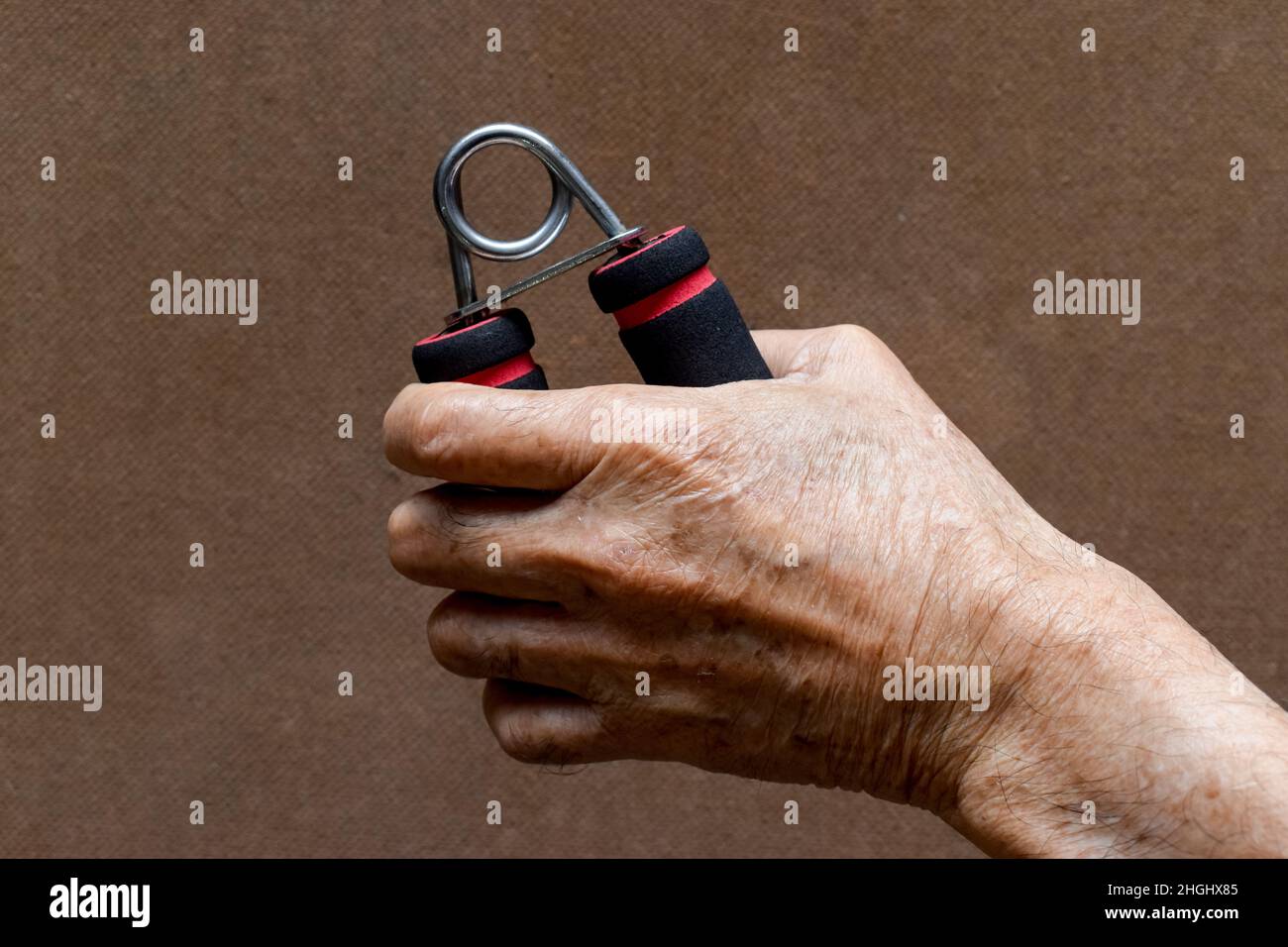 Hand of Southeast asian, Chinese old man gripping hand exercise gripper ...