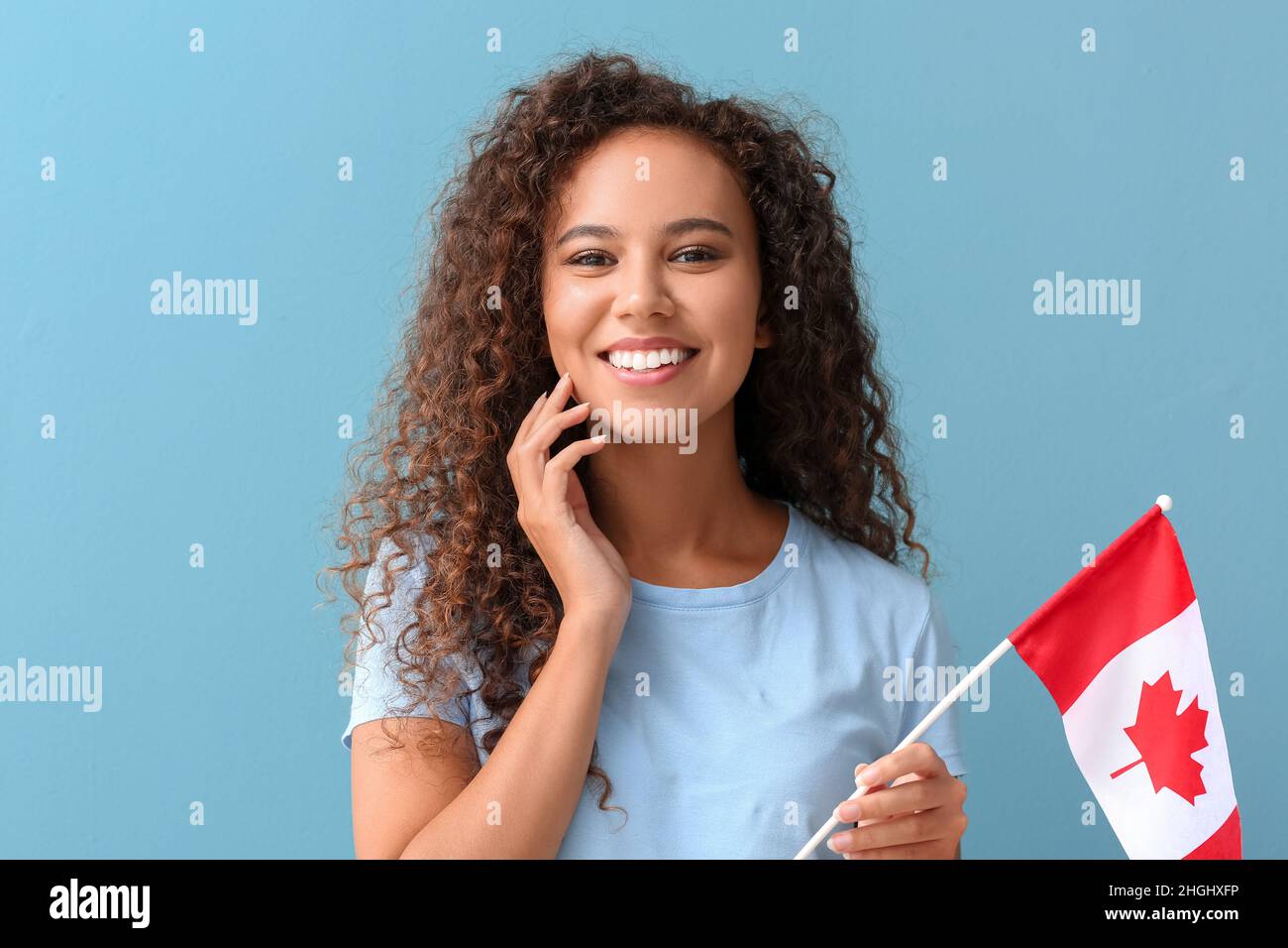 Beautiful young African-American woman with Canadian flag on color ...