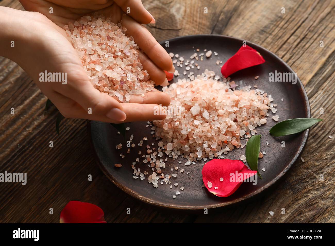 Female hands with pink sea salt on wooden background, closeup Stock ...