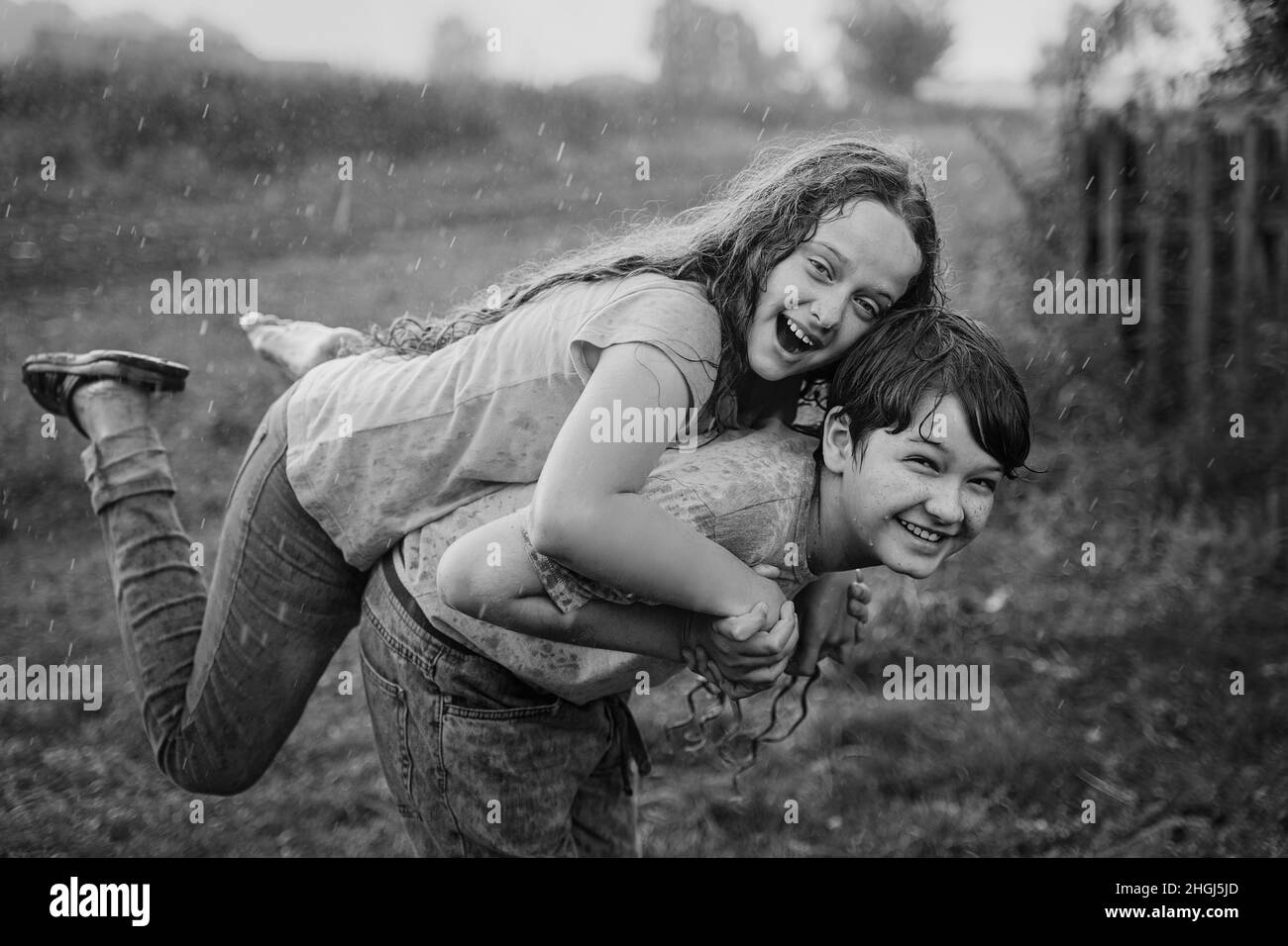 Happy children with piggyback riding playing in the rain, black and ...