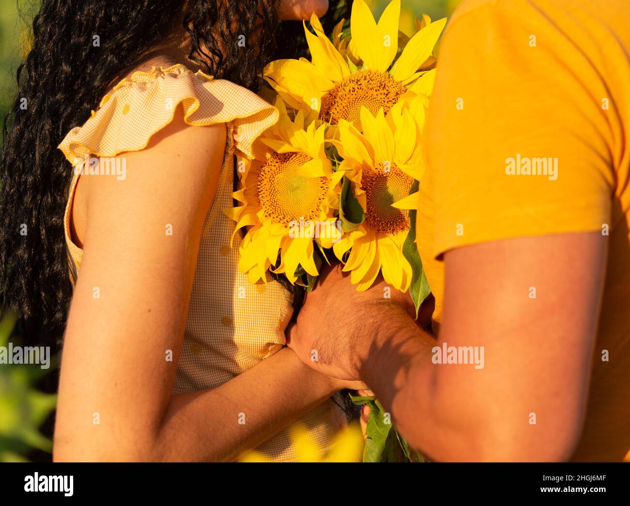 couple holding bouquet of sunflowers standing together in a field in ...