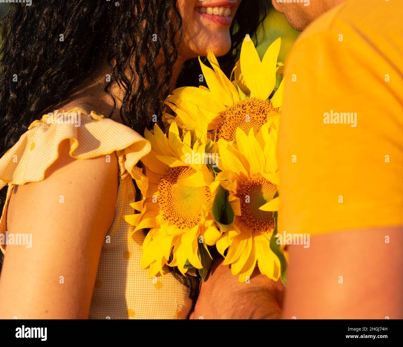 couple holding bouquet of sunflowers standing together in a field in ...