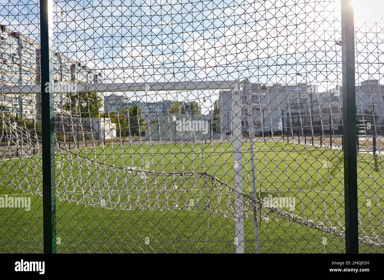 Lawn field for playing football behind the green fence mesh. Close-up ...