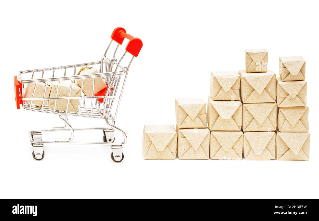 Miniature shopping trolley standing by a pile of small boxes isolated ...