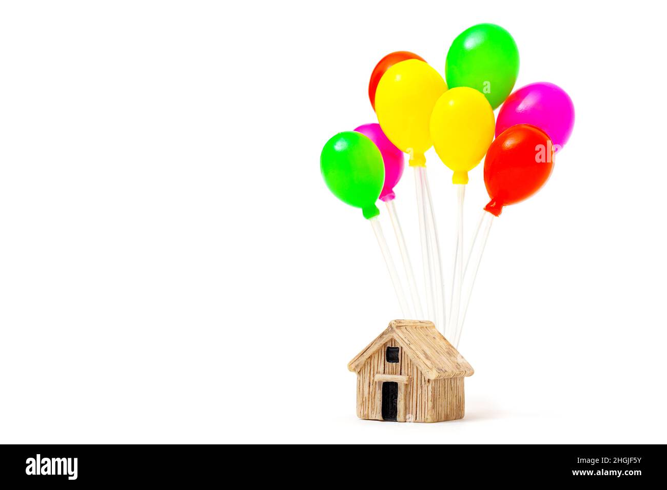 Miniature wooden house with a cluster of multicolored balloons isolated ...