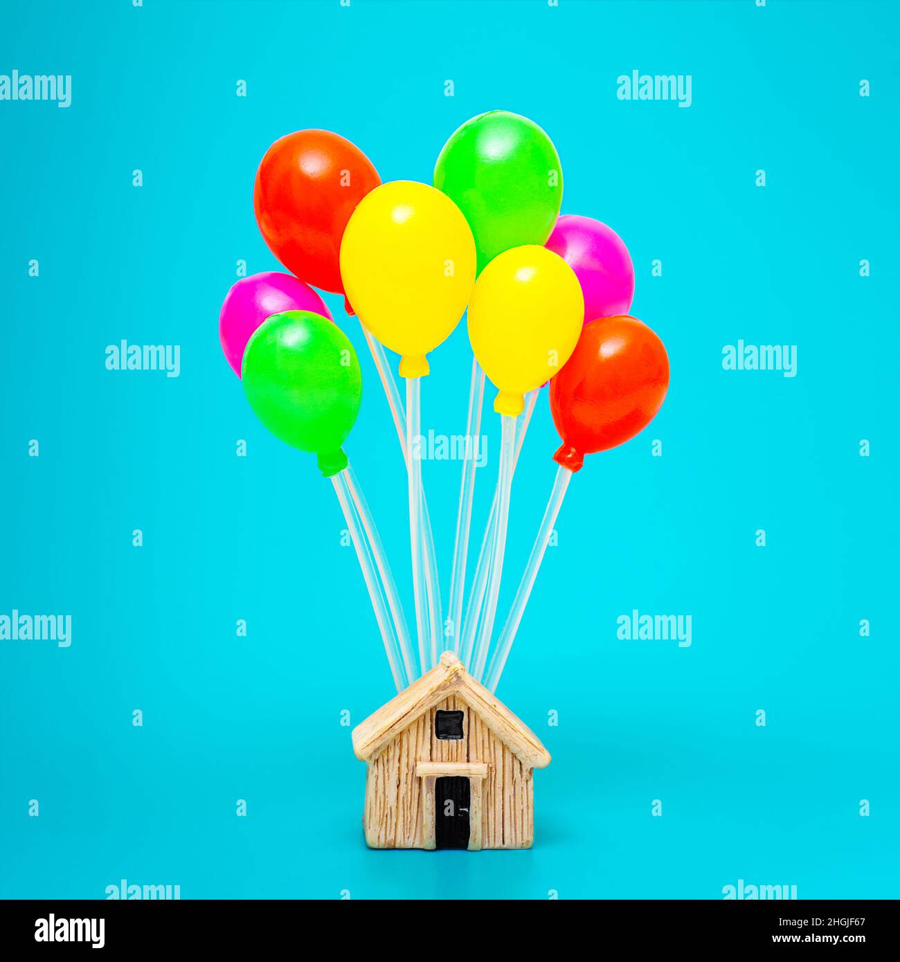 Miniature house with a bunch of multicolored balloons isolated on a ...