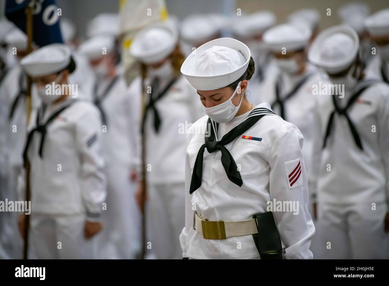 Graduating Sailors bow their heads for a prayer during a pass-in-review ...