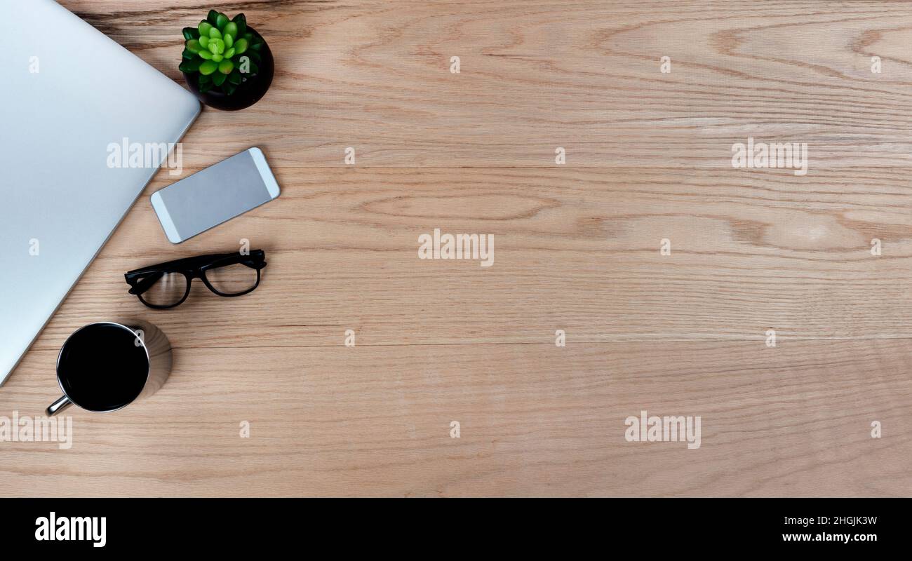 Oak wood office desk table with closed laptop computer, cup of coffee ...