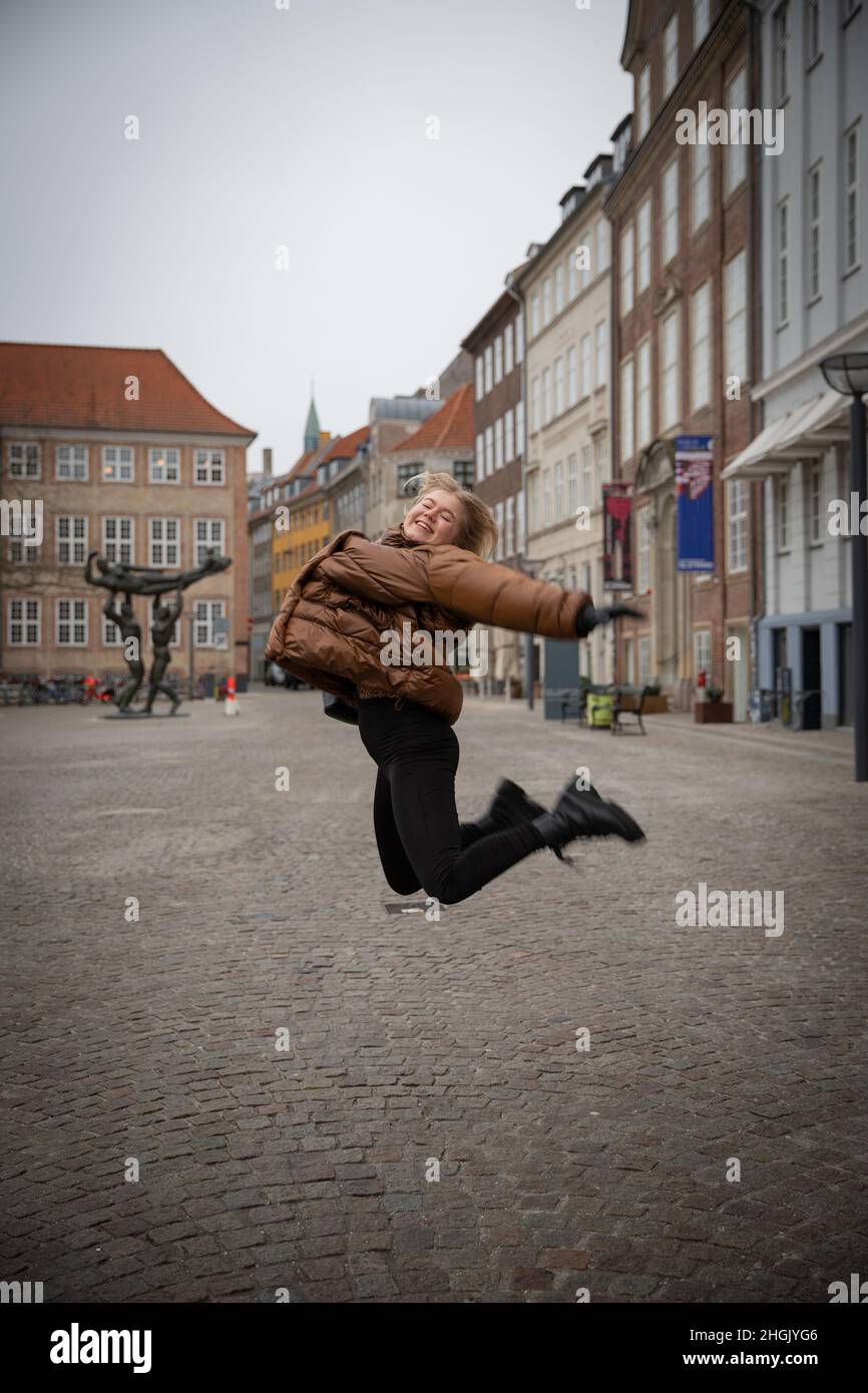 Happy young girl jumps in the air with open arms and smiles. Concept of ...