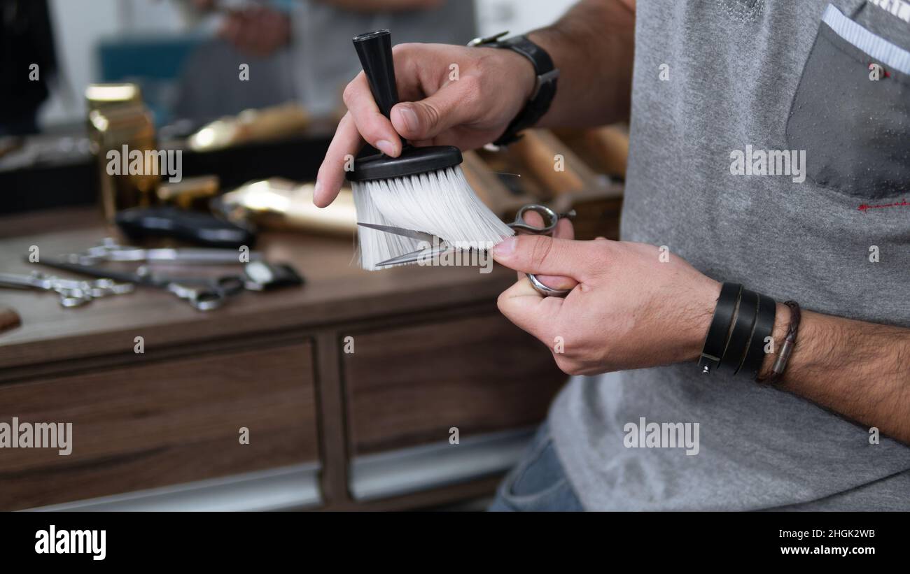 Detail of professional barber cleaning scissor with soft brush at ...