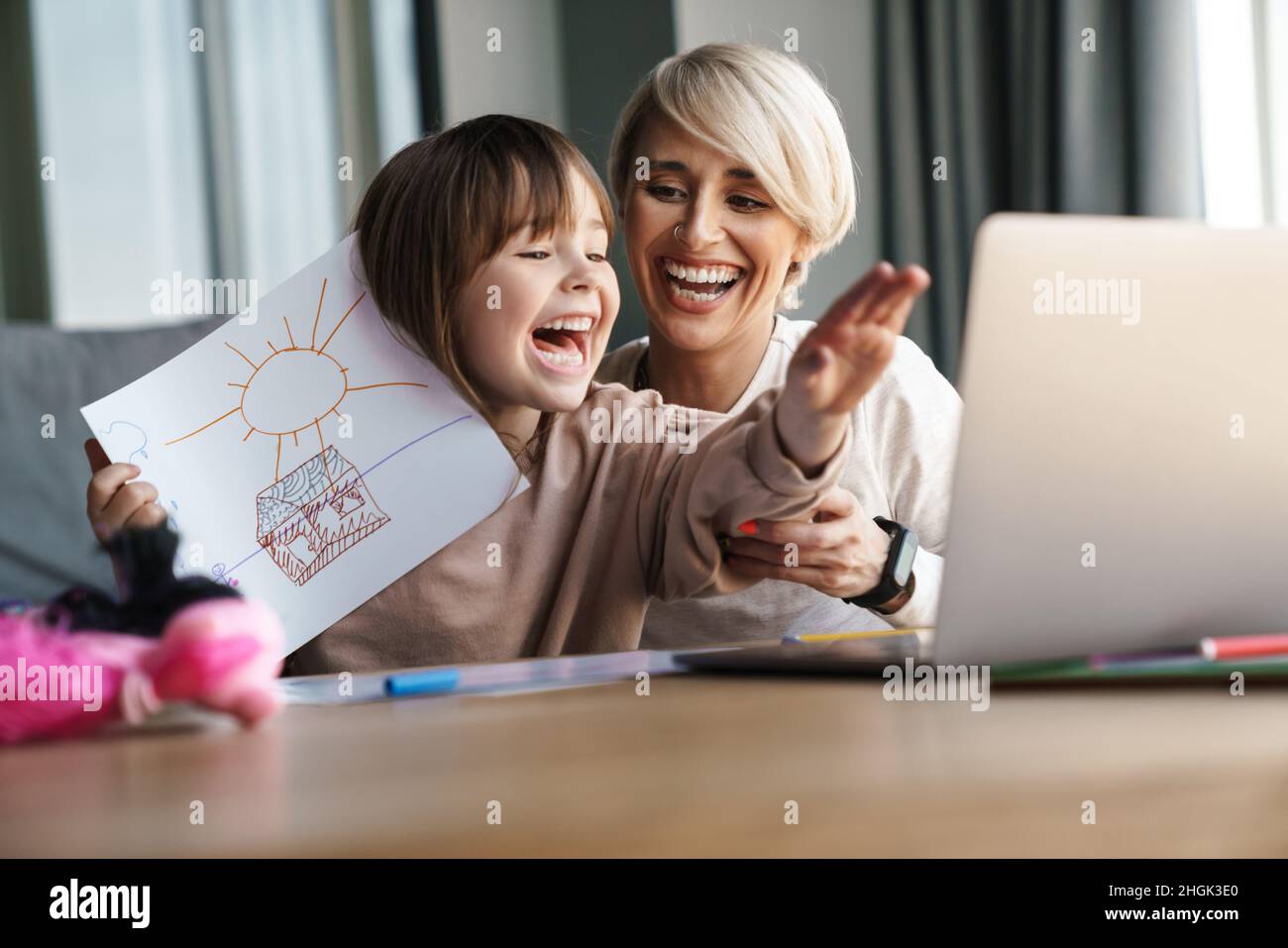 Mother helping her daughter with school homework, using laptop computer ...