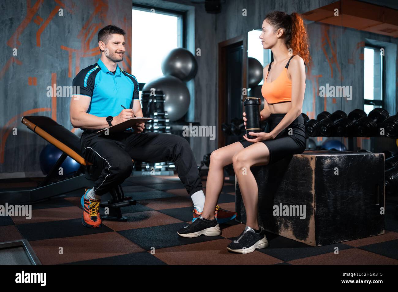 young personal trainer man talking with woman athlete and plan workout ...