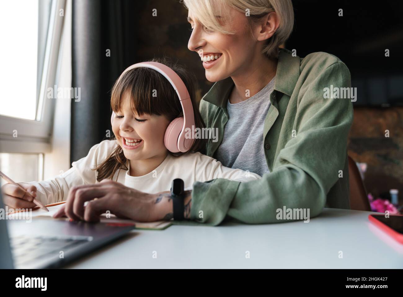 Happy mother helping her daughter with school homework, using laptop ...