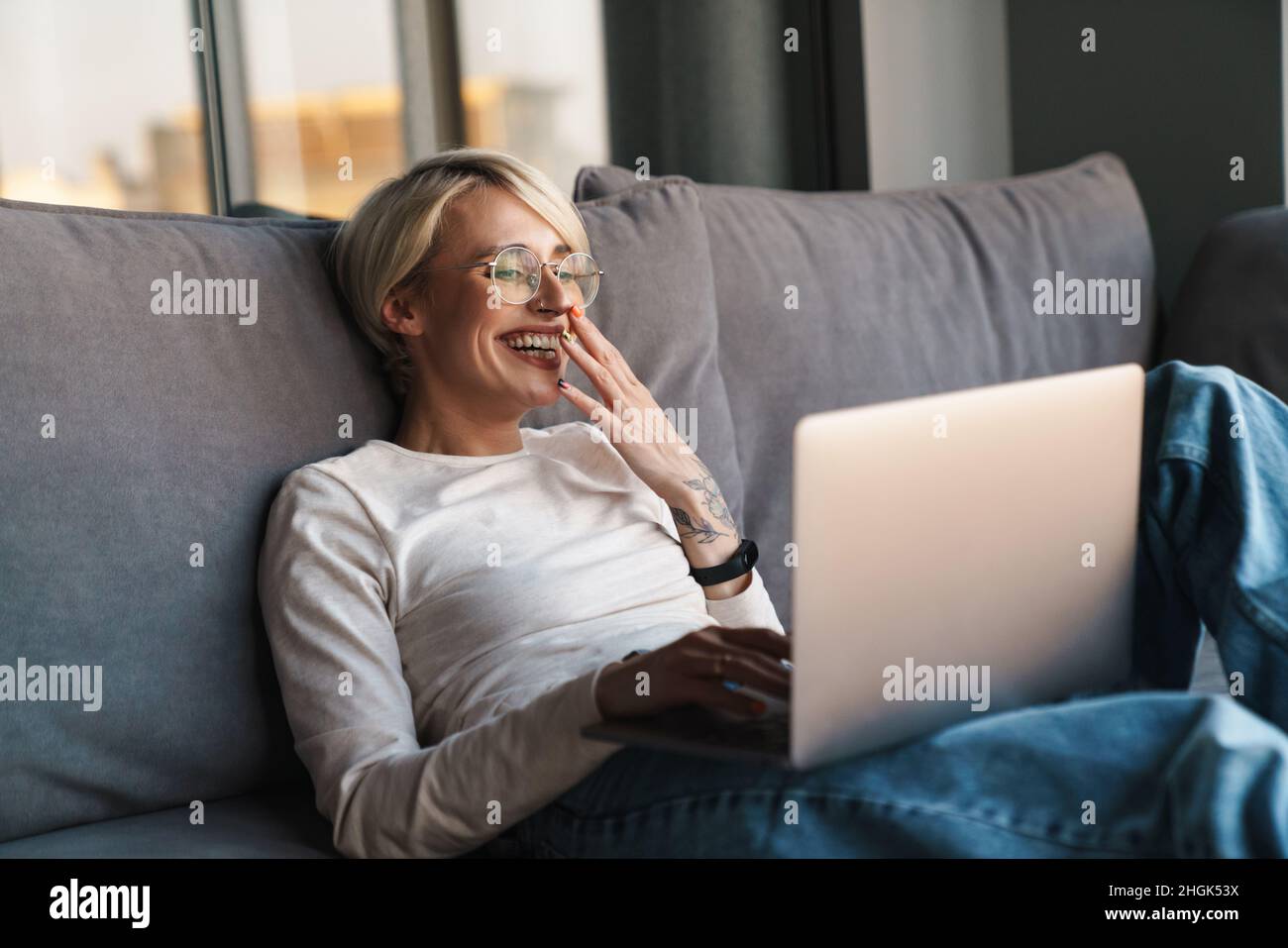 Smiling laughing mid aged blonde woman studying online via laptop ...