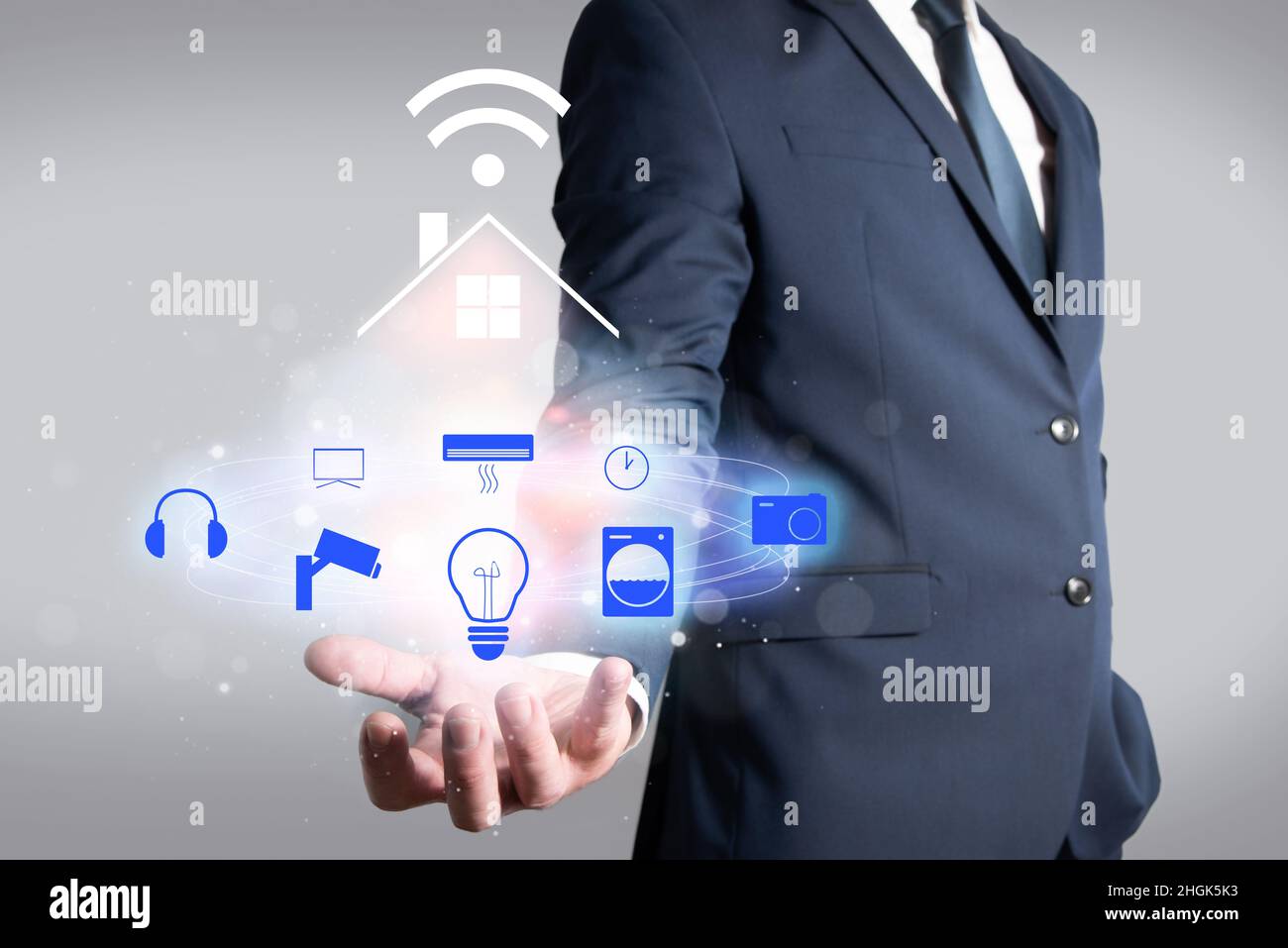 Man in jacket holding a house connected by wifi to different electronic ...