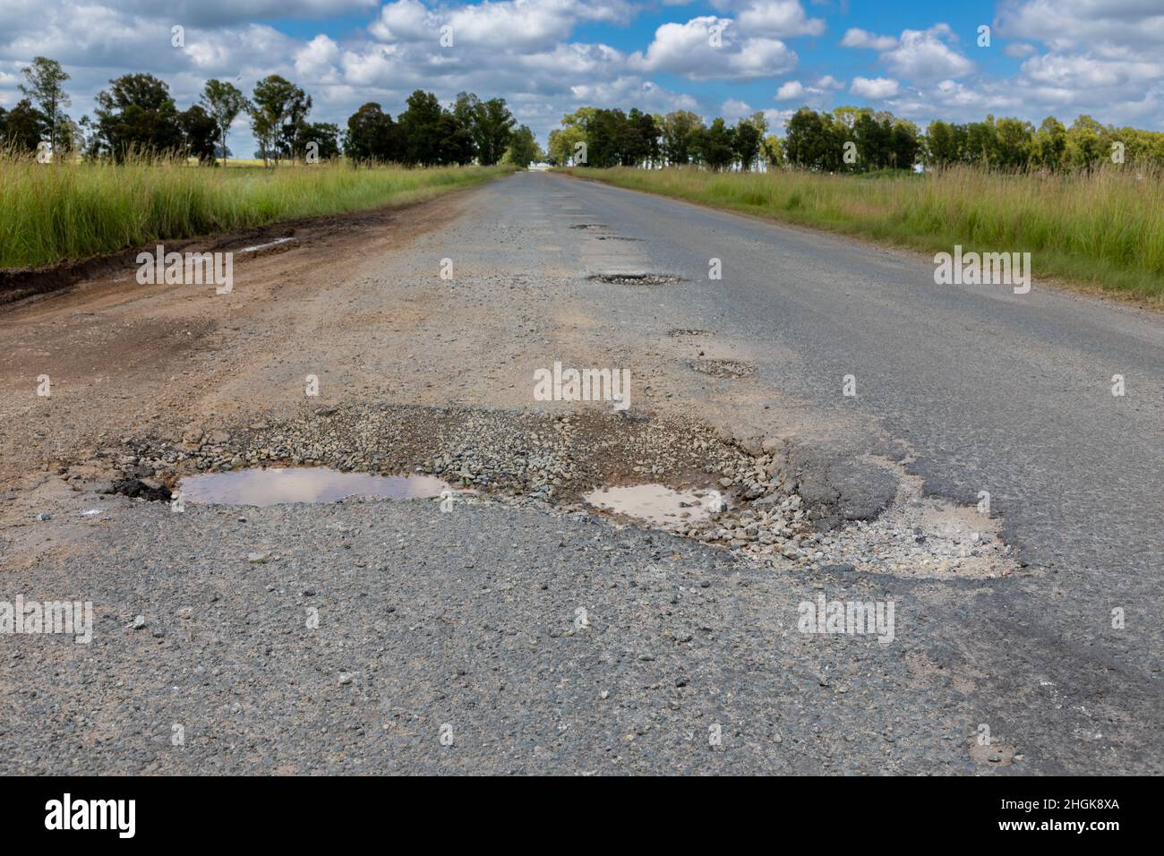 Asphalt road with a very large and deep pothole. Pothole is half filled ...