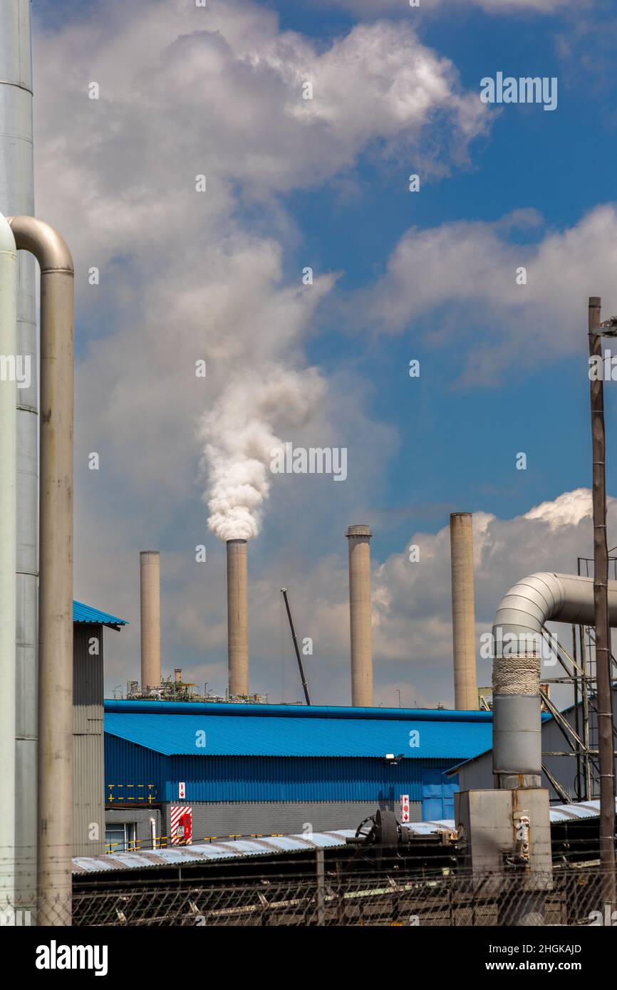 Four smoke stacks in an industrial plant with think smoke coming from ...