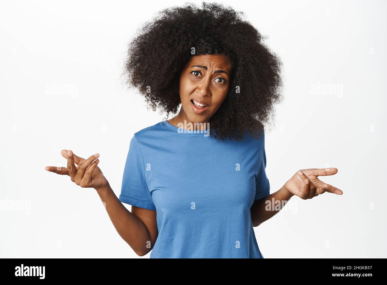 Image of annoyed and confused Black woman shrugging shoulders, so what ...