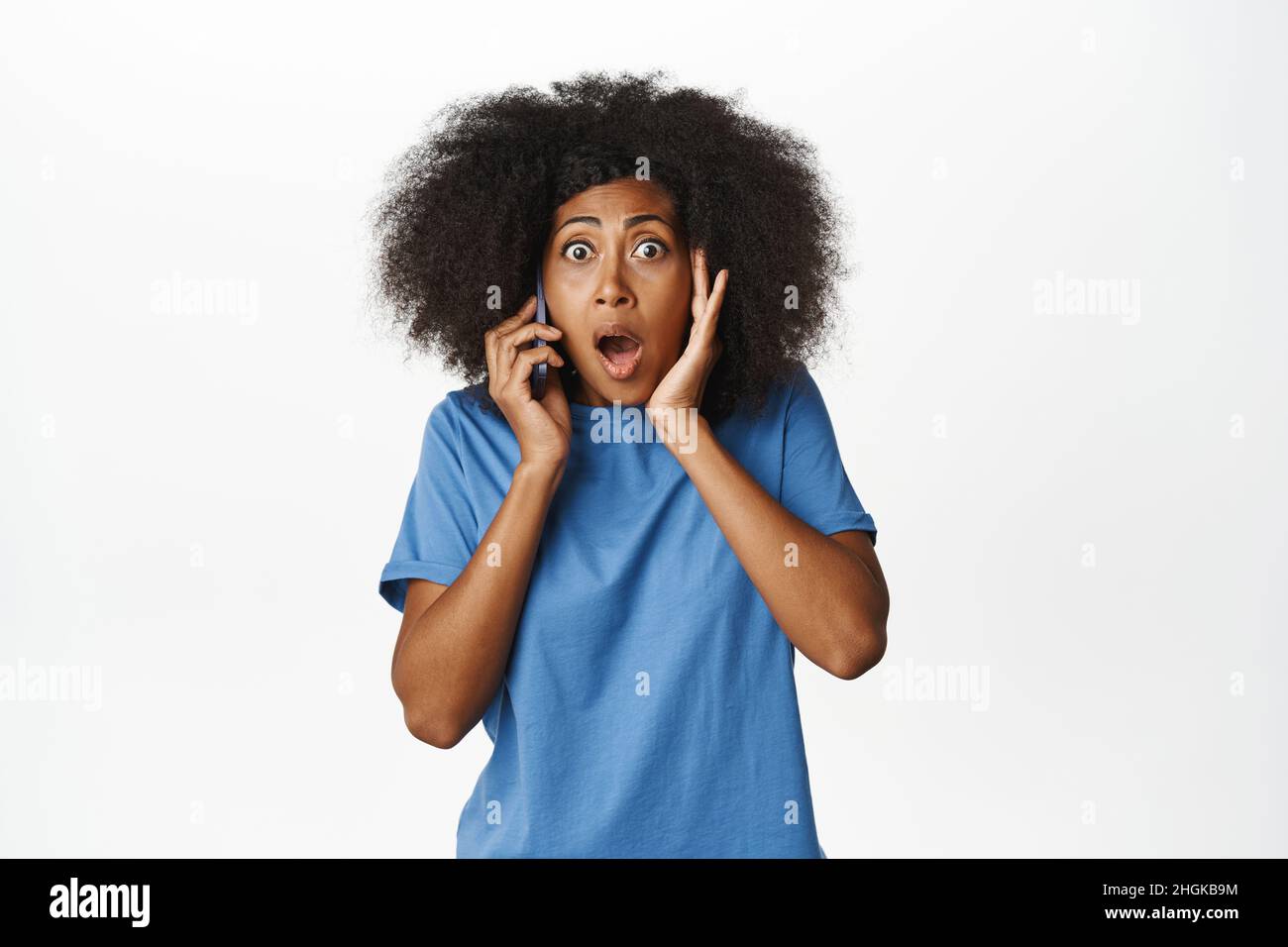 Shocked woman answer phone call, looks scared and worried, standing in ...