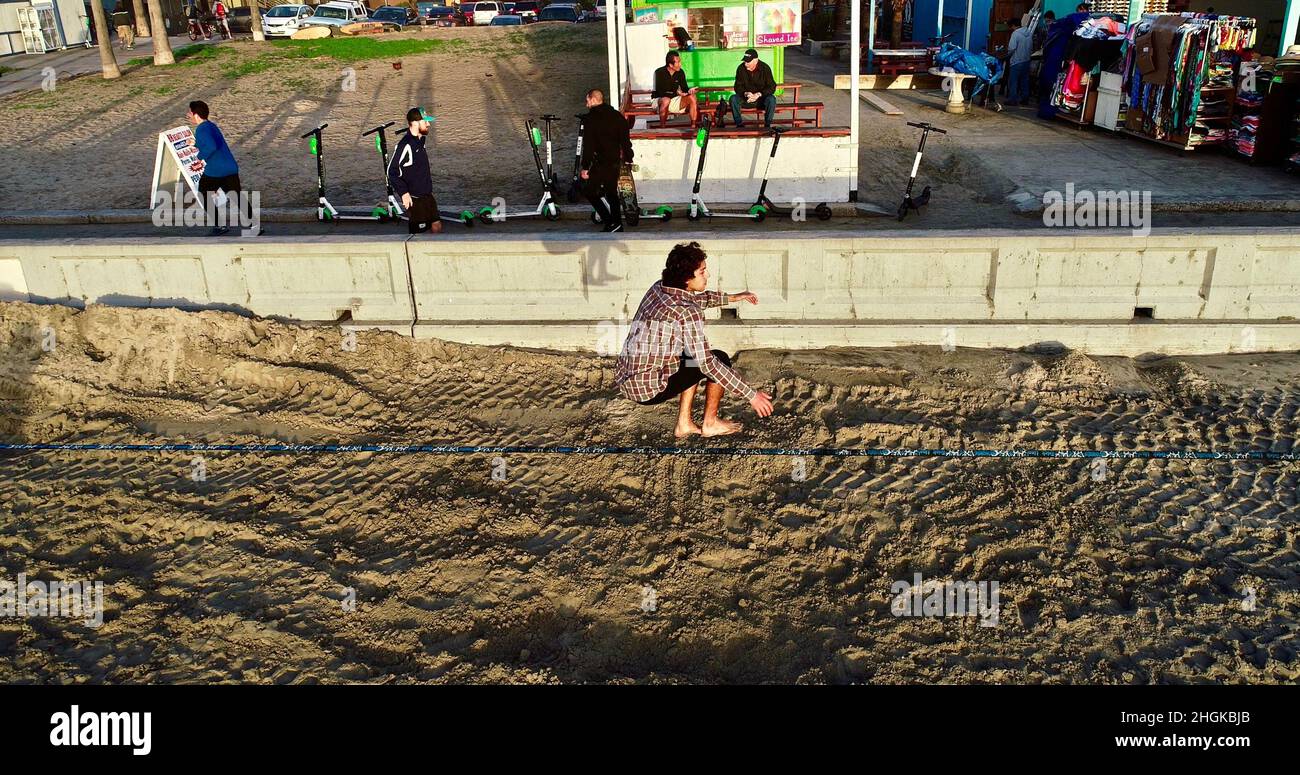 Aerial view above male slackliner balancing on rope and doing ...