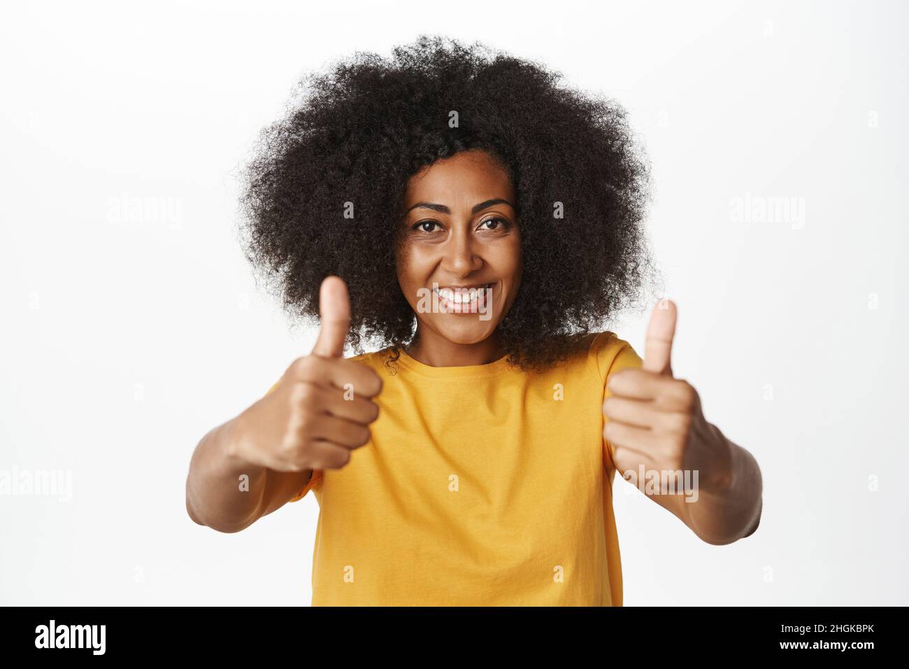 Pleased african woman shows thumbs up, smiling pleased, recommending ...